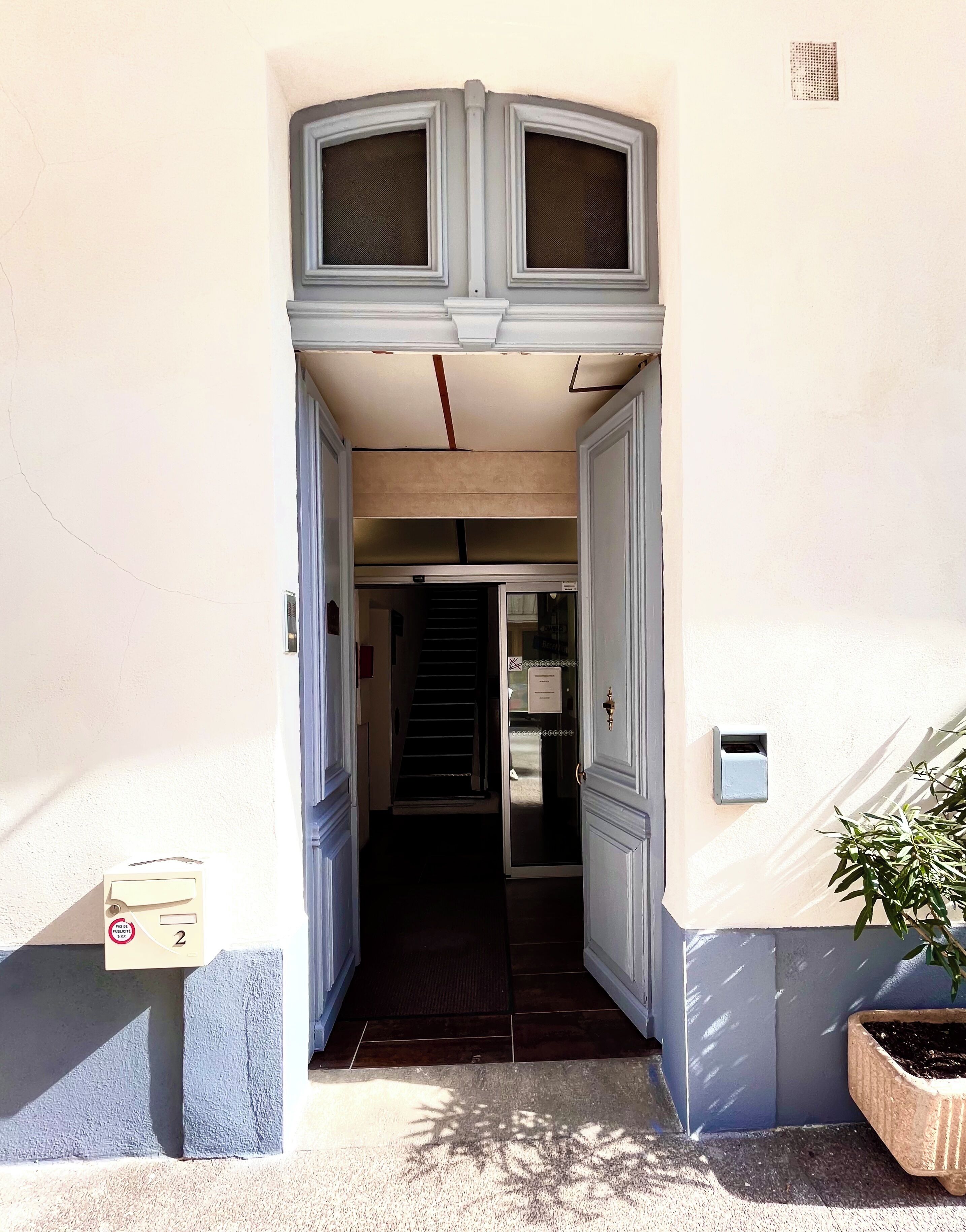 Uma porta com uma pequena caixa de correio e uma planta do lado direito.
