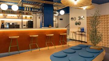 Uma área de bar com banquetas, balcão e luminárias pendentes.