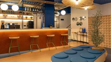 Uma área de bar com banquetas, balcão e luminárias pendentes.