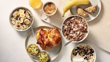 Uma mesa de café da manhã com diversos pratos, incluindo mingau de aveia, café, um croissant e uma banana.
