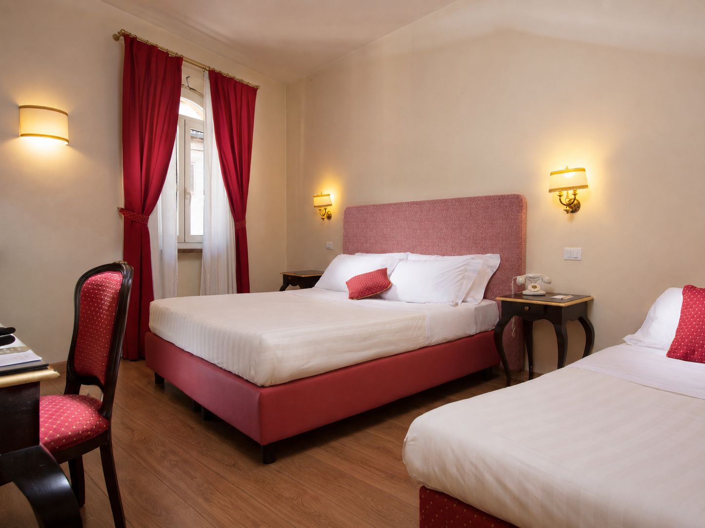 Quarto de hotel com duas camas, uma escrivaninha e uma cadeira.