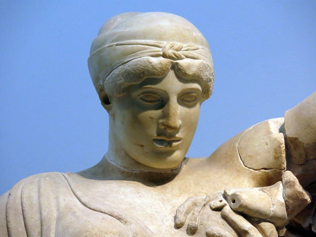 Uma estátua de mármore com cabeça e parte superior do tronco ricamente detalhada.