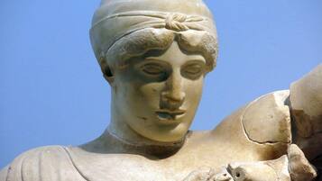 Uma estátua de mármore com cabeça e parte superior do tronco ricamente detalhada.
