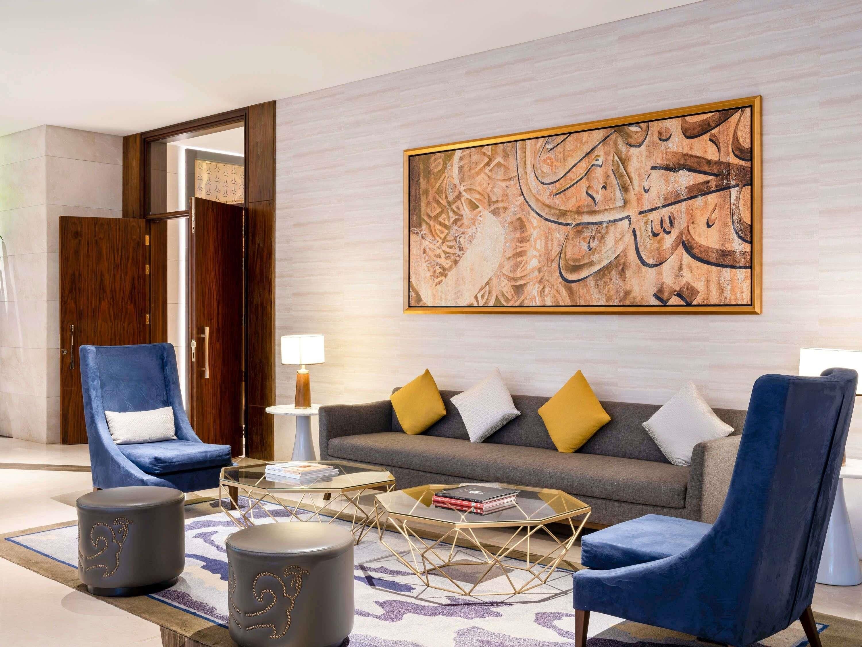 Uma sala de estar moderna com um sofá, duas poltronas, uma mesa de centro e um objeto decorativo na parede.