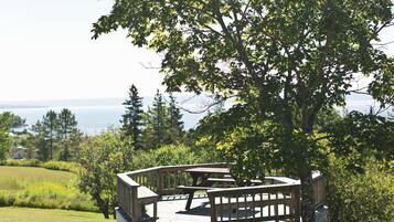 Um deck de madeira com mesas de piquenique com vista para um lago.