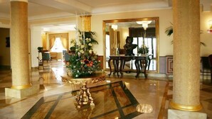 Um saguão com piso de mármore, um grande candelabro e um balcão de recepção.