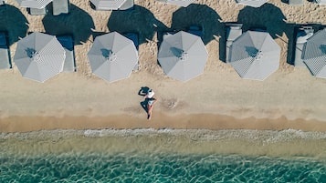 Na praia, espreguiçadeiras, guarda-sóis, toalhas de praia