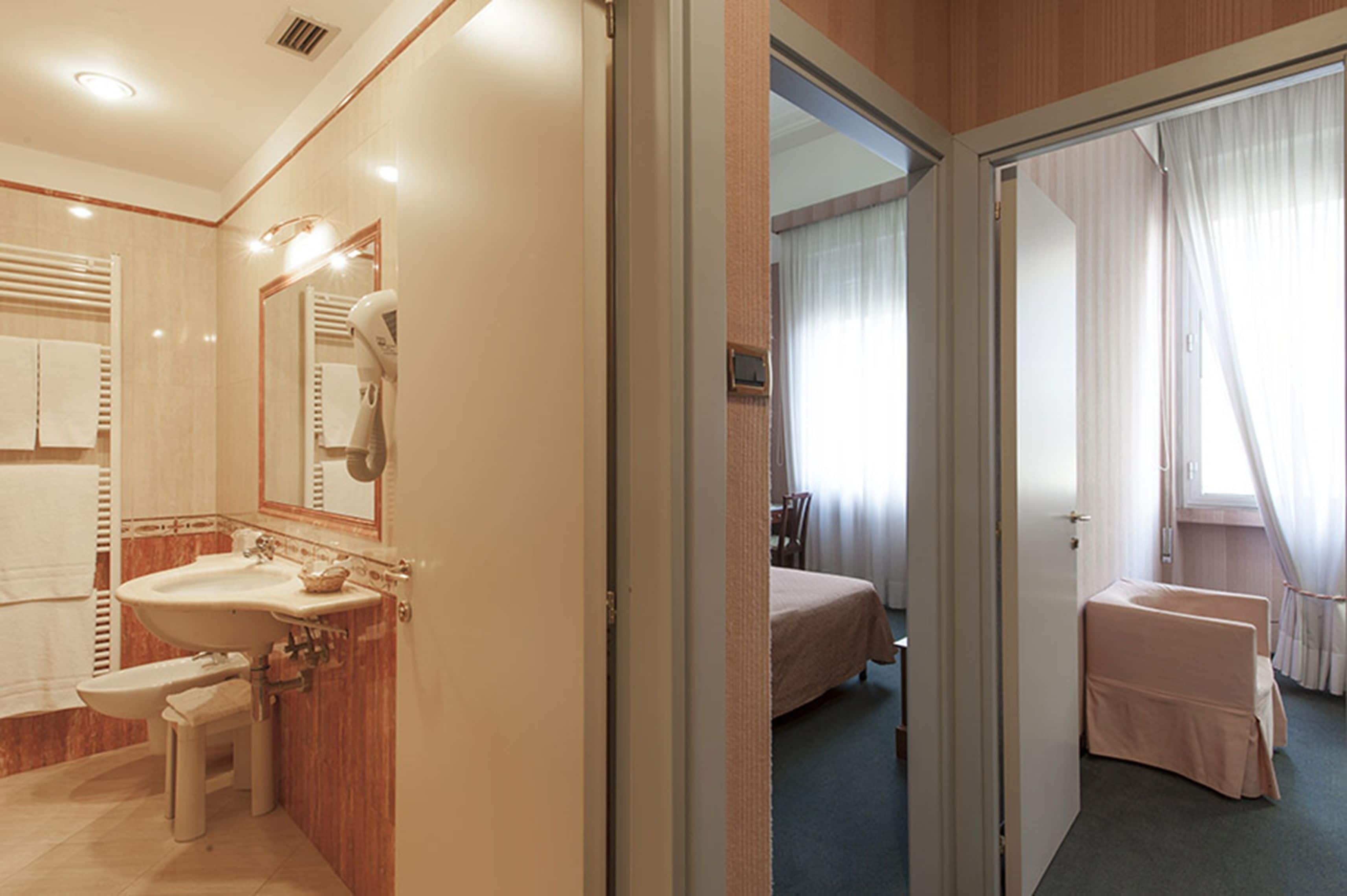 Uma casa de banho de hotel com lavatório, espelho e porta-toalhas.