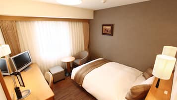 Quarto de hotel com uma cama, uma escrivaninha com computador, uma cadeira e uma mesinha.
