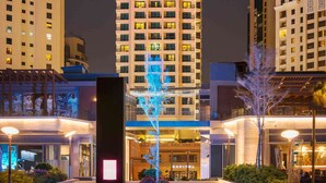 Hotel moderno com um pátio central, iluminado por iluminação decorativa e uma escultura de destaque.
