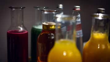 Uma fileira de garrafas de vidro transparente com líquidos de cores diferentes, possivelmente para uso científico ou culinário.