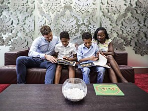 Um grupo de quatro pessoas sentadas num sofá de couro castanho, lendo um livro em conjunto.