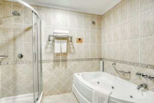 Um banheiro com box de vidro, banheira branca e porta-toalhas com toalhas.