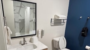 Uma casa de banho moderna com lavatório, espelho, sanita e um porta-toalhas.