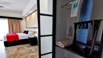 Quarto de hotel com uma cama, banheiro com porta-toalhas e janela com cortinas.