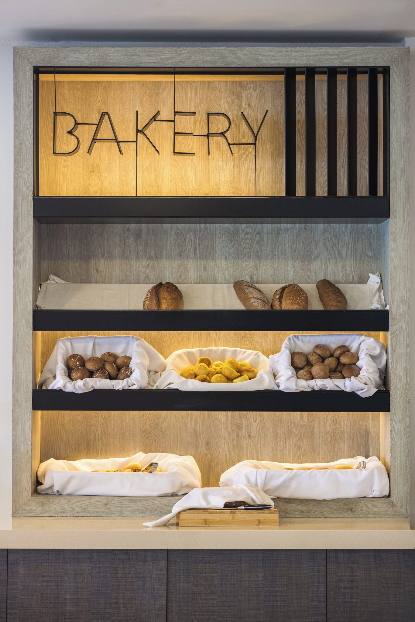 Vitrine de padaria com prateleiras de madeira, pão e doces.