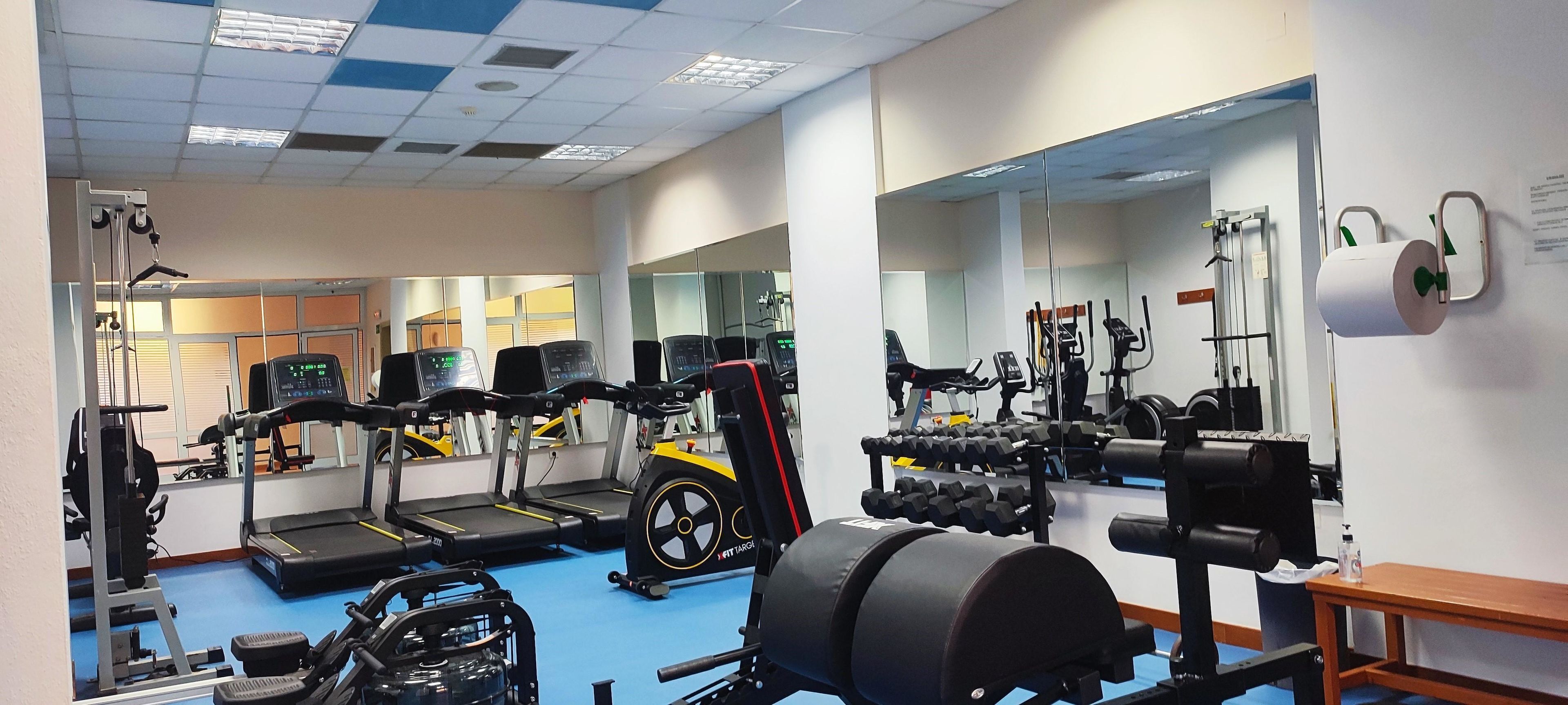 Uma academia com esteiras, aparelhos de musculação e pesos livres.