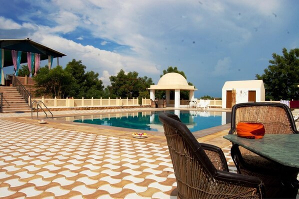 Uma área de piscina com deck revestido, espreguiçadeiras e um gazebo.