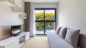 Uma sala de estar moderna com televisão de tela plana, um sofá cinza e estantes embutidas.
