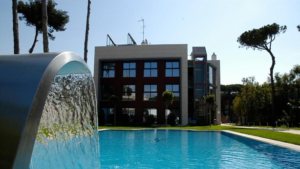 Um edifício moderno com piscina em frente.
