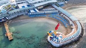 Vista aérea de um resort com uma piscina grande, área de praia e várias áreas de estar cobertas.