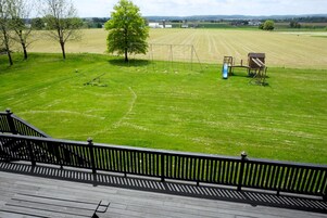 Um campo gramado com um parquinho e um deck de madeira.