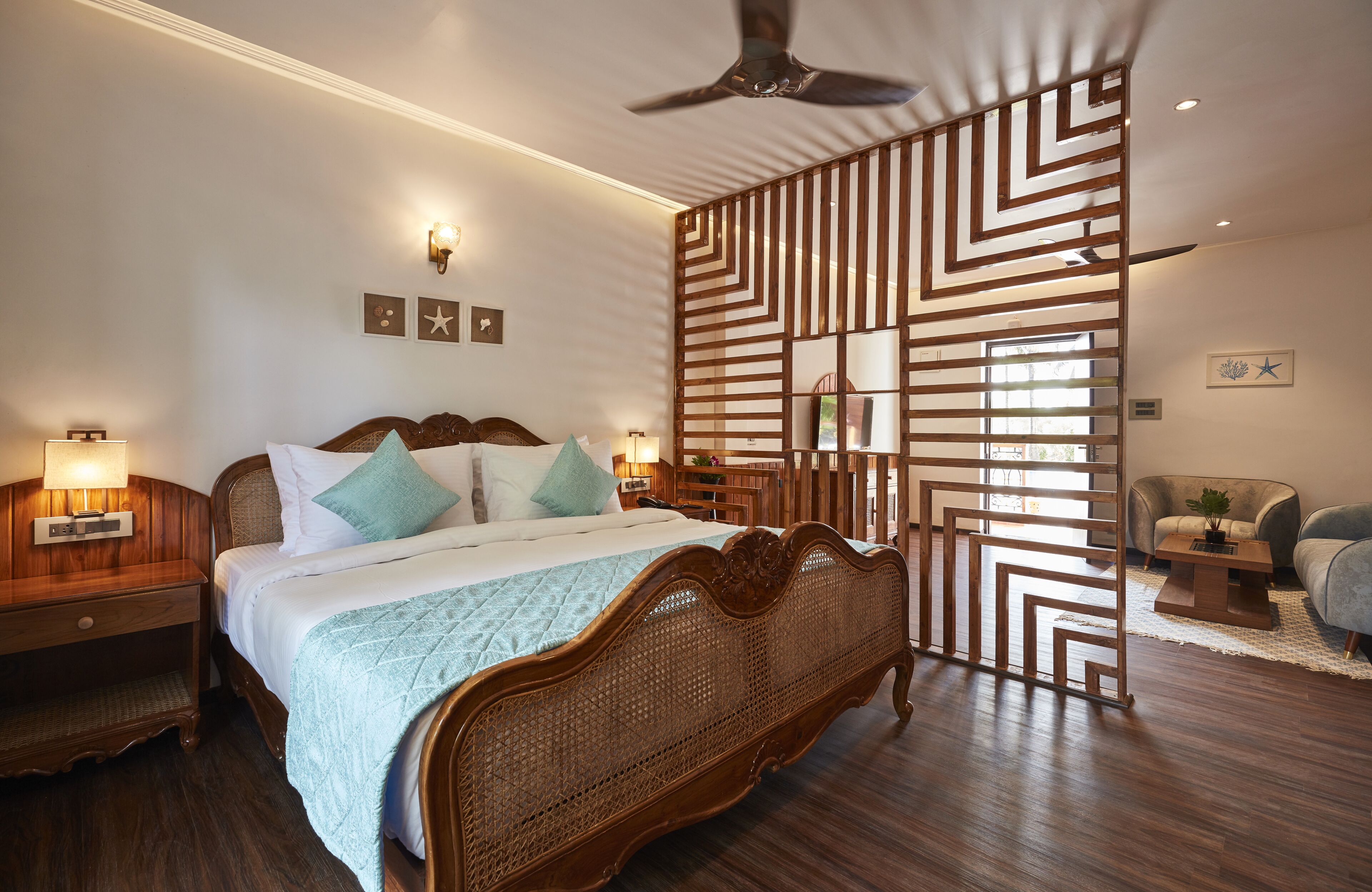 Quarto com cama de madeira, luminárias de cabeceira, ventilador de teto e divisória decorativa.