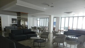 Um hall amplo com design moderno, com sofás, poltronas e uma mesa de centro.