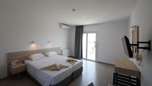 Quarto de hotel moderno com uma cama grande, mesas de cabeceira, escrivaninha e televisão.