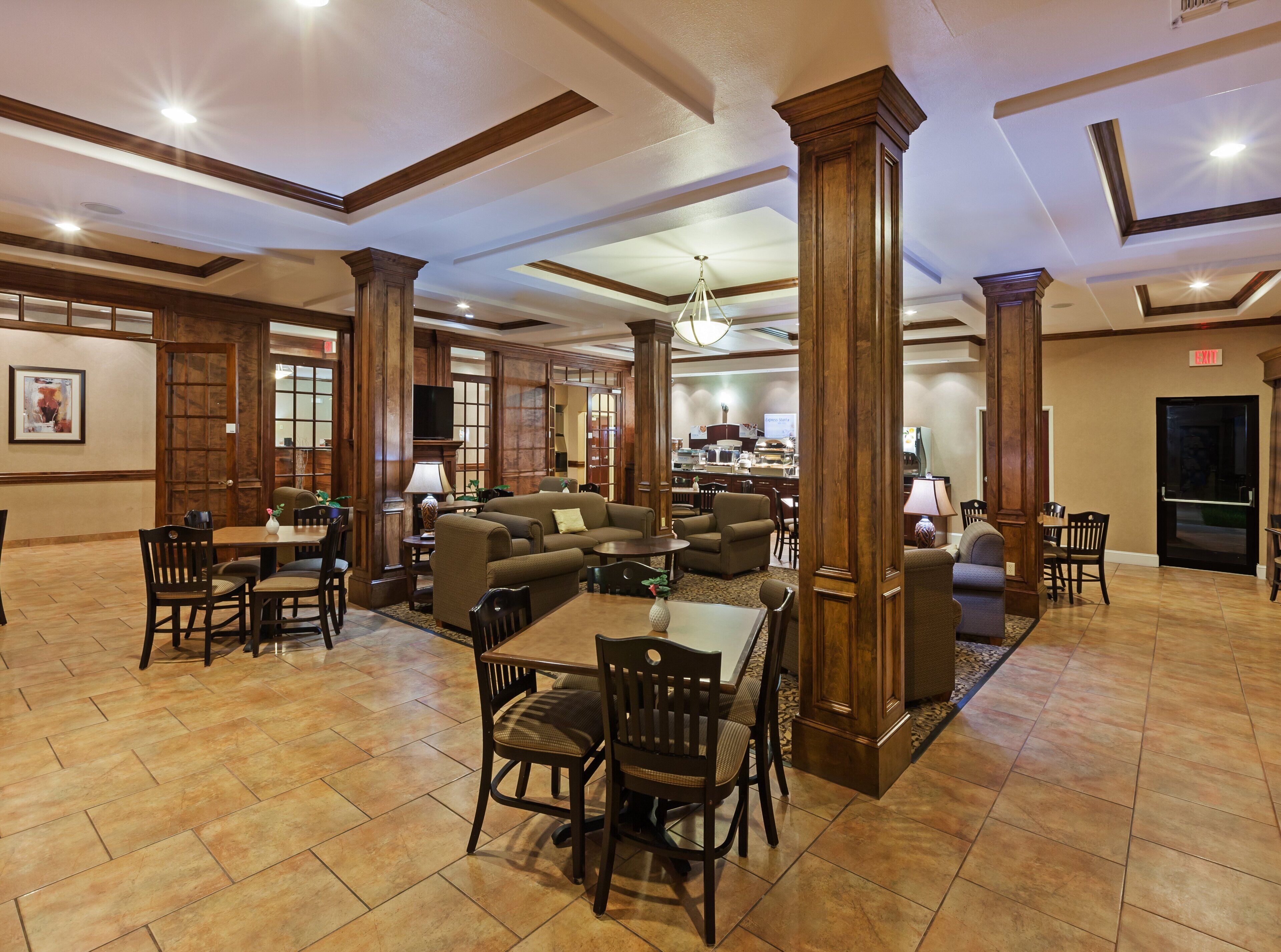 Um saguão de hotel com área de refeições, sofás e bar.