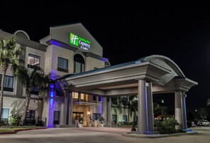 Um hotel Holiday Inn Express & Suites com entrada coberta e fachada de pedra.