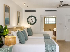 Um quarto moderno com uma cama, abajures, um relógio, uma janela e uma porta.