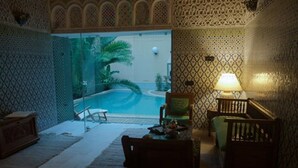 Um quarto com piscina, uma mesa com cadeiras e um abajur.