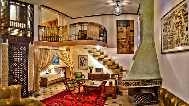 Um interior tradicional com cama, área de estar, escada e lareira.