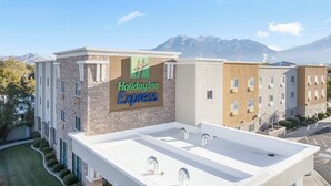 Edifício Holiday Inn Express com piscina no terraço e vista para montanhas.