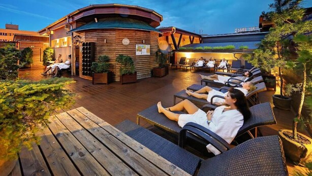 Uma área de estar no terraço com espreguiçadeiras e um edifício de madeira com design circular.