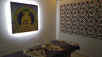 Quarto com área de meditação, com pintura de Buda e parede estampada.