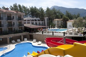 Um resort com piscina, espreguiçadeiras e montanhas ao fundo.