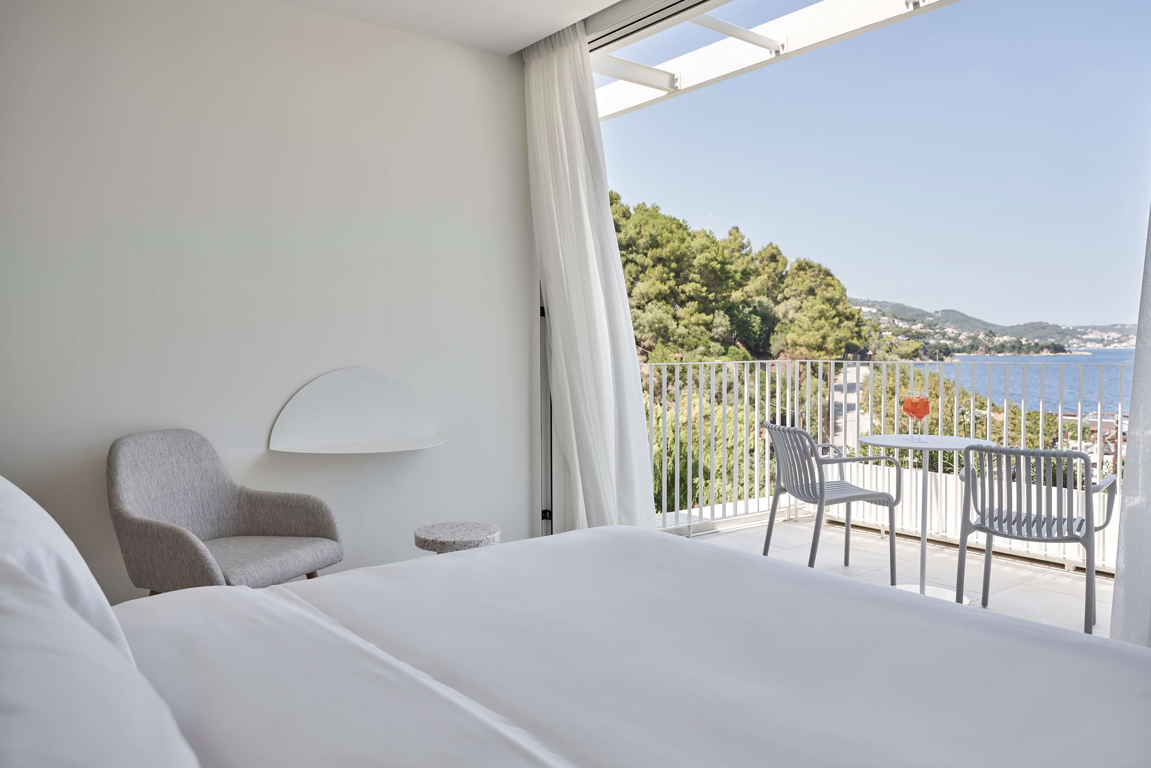 Quarto de hotel com varanda, uma cama, uma cadeira e uma mesa.