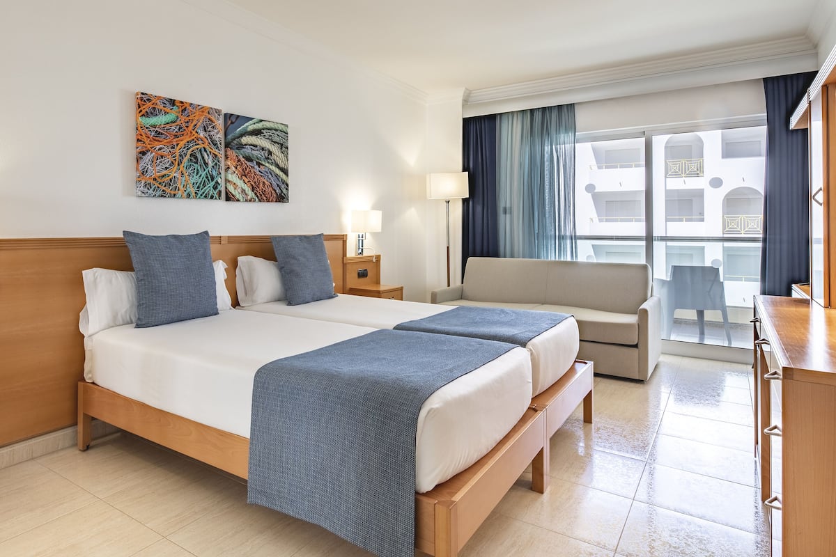 Quarto de hotel com uma cama grande, duas mesas de cabeceira, uma escrivaninha e uma cadeira.