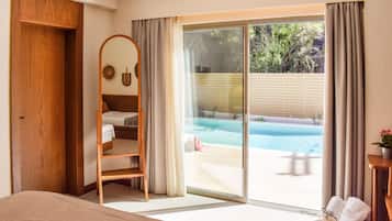 Quarto com uma cama grande, um guarda-roupa de madeira, um pequeno espaço de estar com um banco e uma porta de vidro deslizante para uma área de piscina.