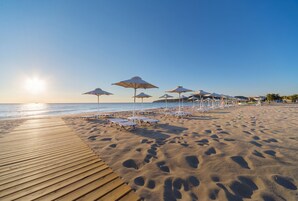 Na praia, espreguiçadeiras, guarda-sóis de praia, toalhas de praia 