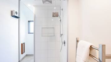 Um banheiro moderno com box de vidro, porta-toalhas e sistema de ventilação visível.