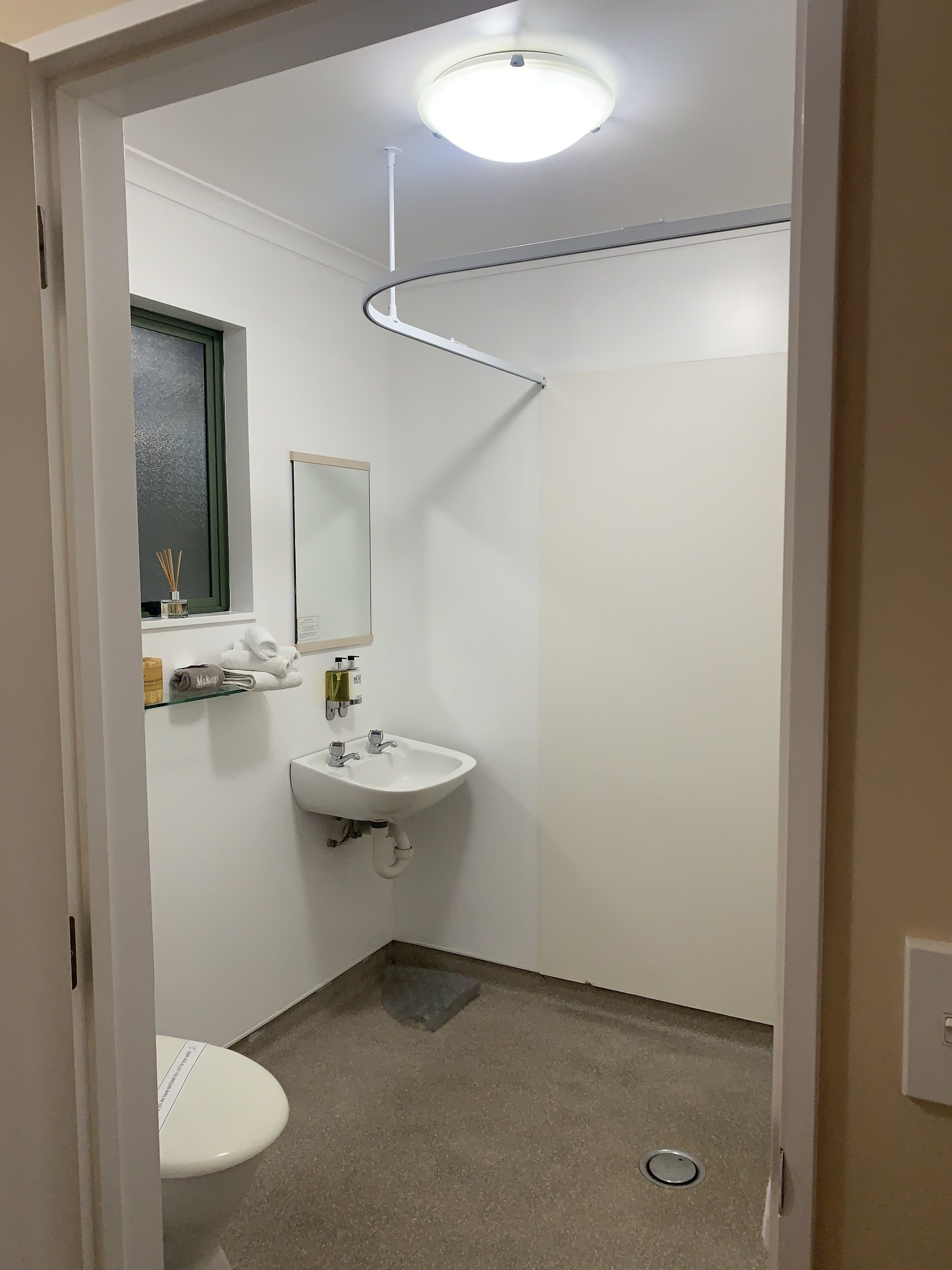 Uma casa de banho pequena e limpa, com uma sanita, um lavatório e um espelho.