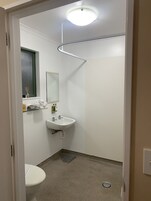 Uma casa de banho pequena e limpa, com uma sanita, um lavatório e um espelho.