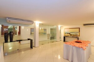 Um hall de hotel moderno com uma mesa de recepção, um painel de vidro e uma mesa com um cobertor.