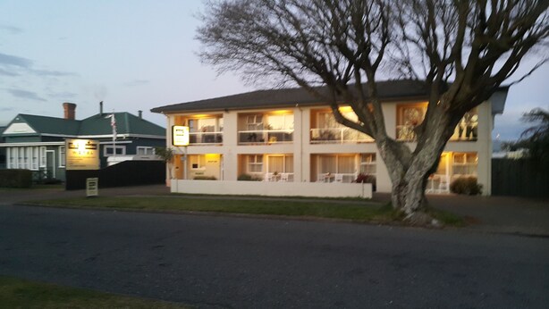 Um motel de dois andares com teto plano, várias janelas e uma placa.