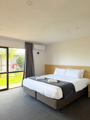 Quarto de hotel com cama grande, janela com cortinas, ar condicionado e vista para o exterior.