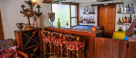 Uma área de bar com móveis de madeira, adega e prateleiras com garrafas.