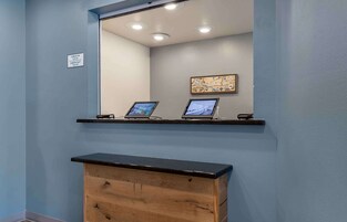 Uma área de recepção com placa de check-in/check-out, um mapa de Austin e dois laptops numa prateleira.